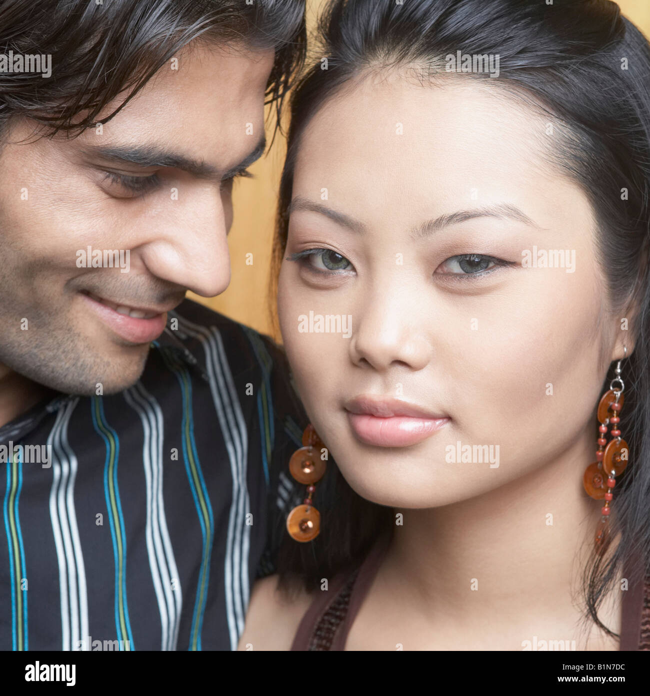 Close-up of a young woman smiling with a young man looking at her face ...