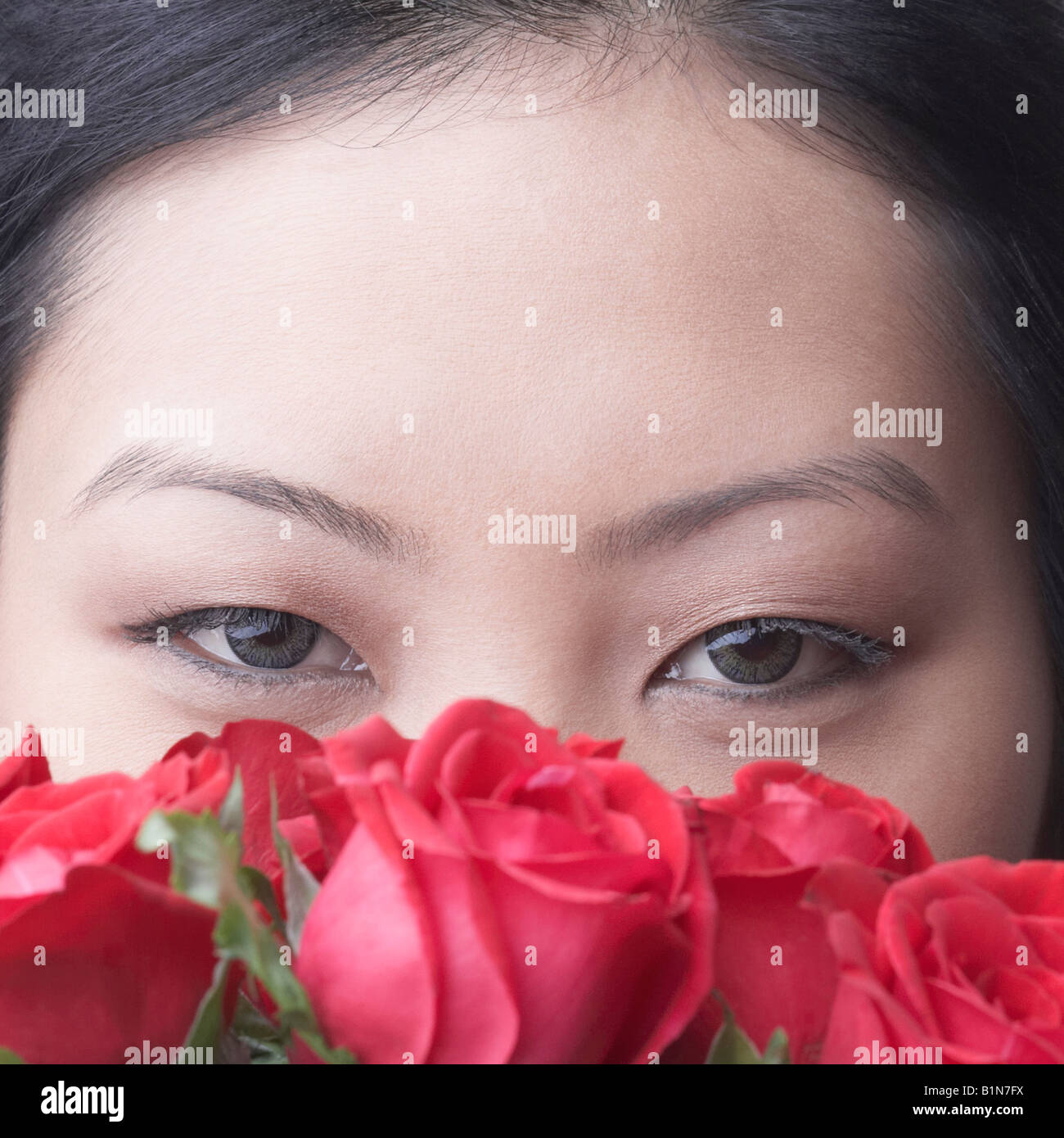 Close-up of a young woman's face behind roses Stock Photo - Alamy