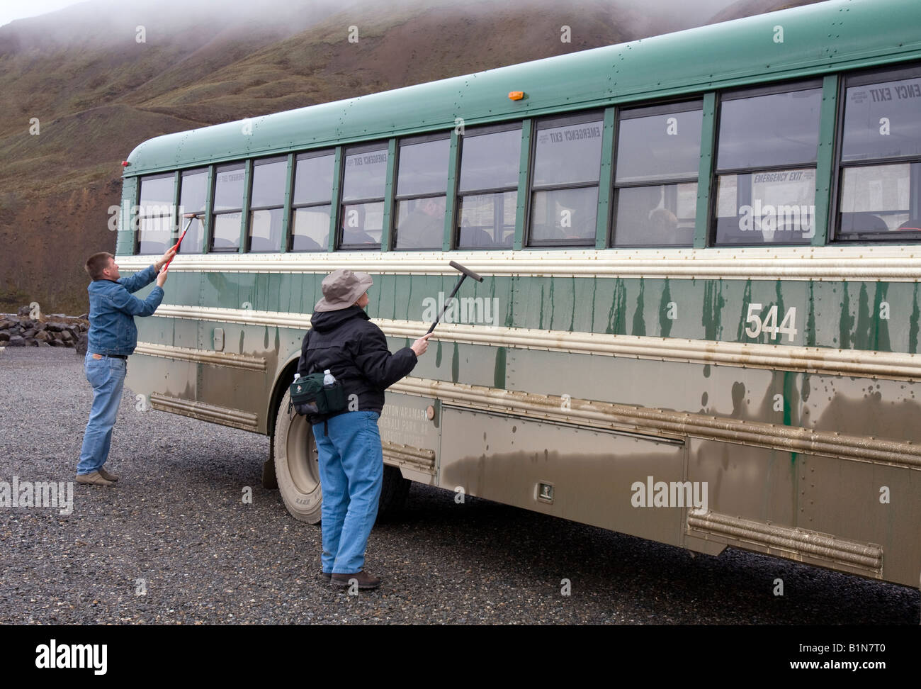 Tourist cleaning the windows of a bus, before driving back out of ...