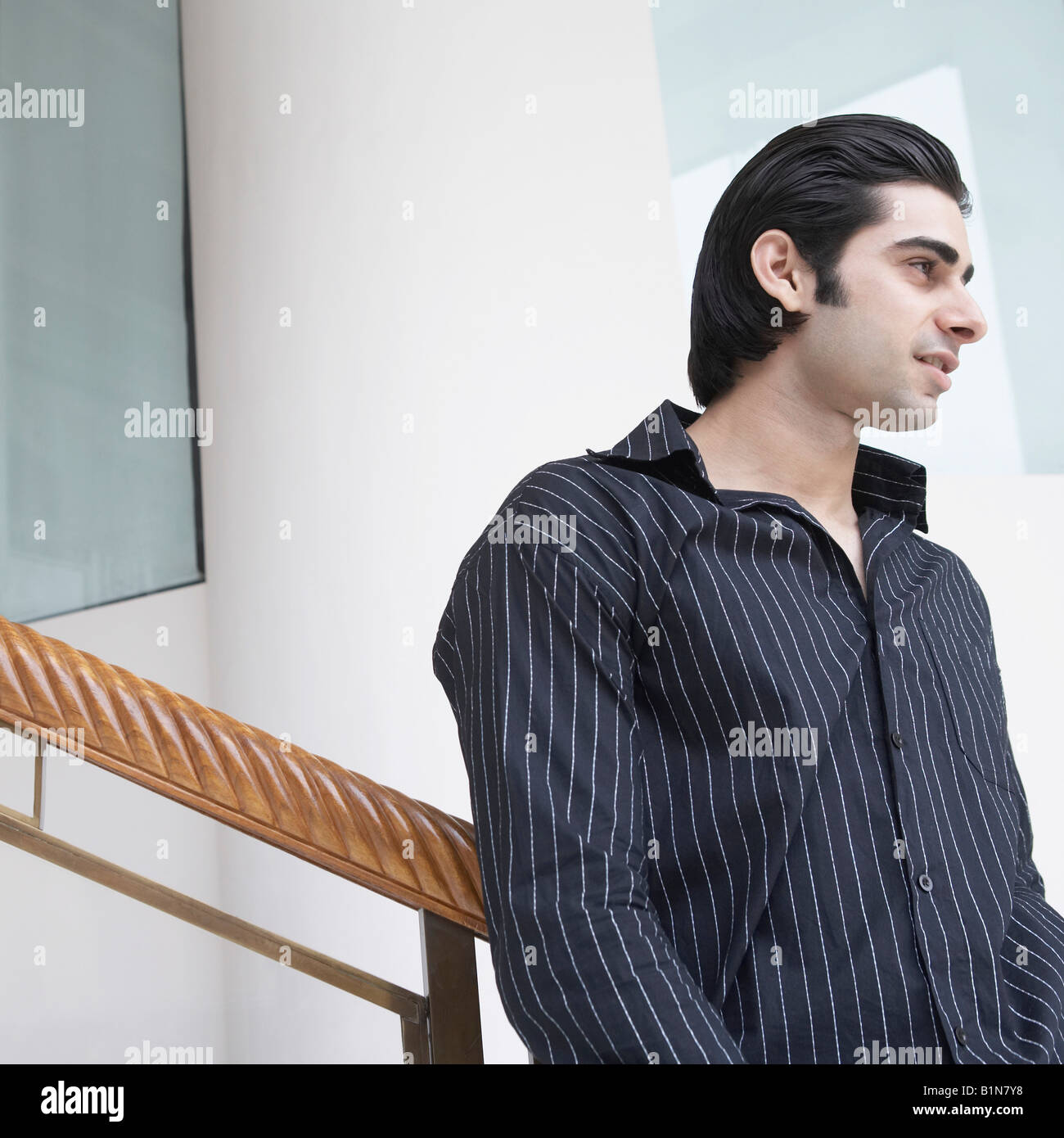 Young man leaning against a banister and looking away Stock Photo - Alamy