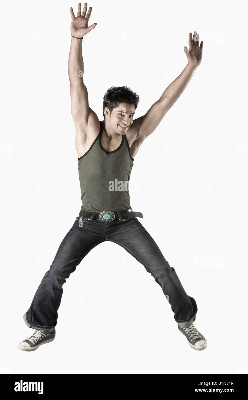Portrait of a young man jumping with his arms raised and smiling Stock ...