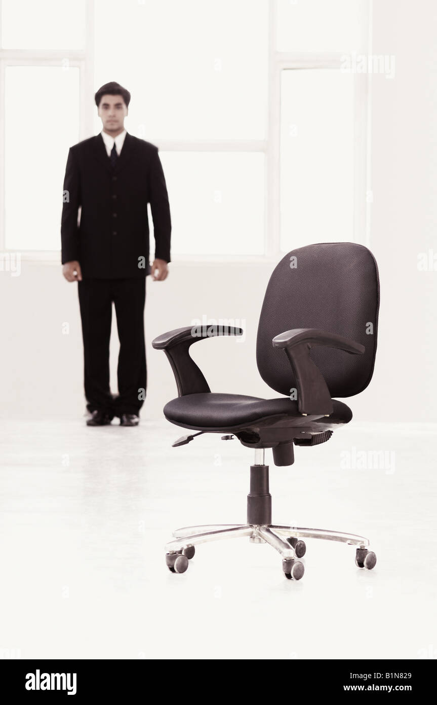 Businessman standing behind a chair in an office Stock Photo - Alamy