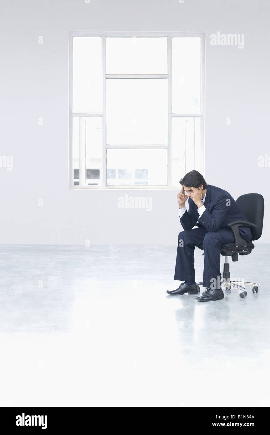 Businessman sitting on a chair and thinking Stock Photo - Alamy