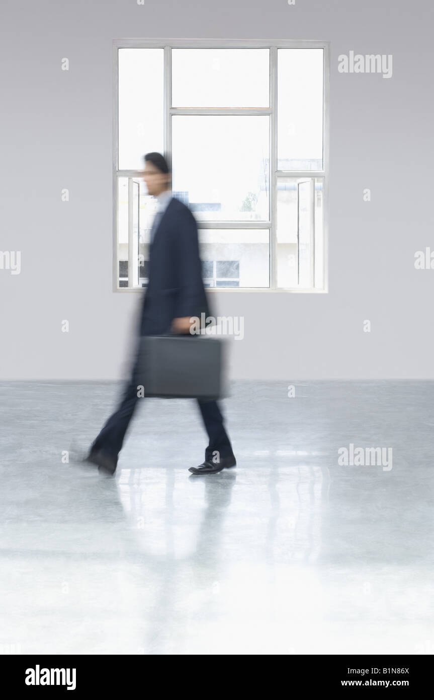 Side profile of a businessman carrying a briefcase in an office Stock ...