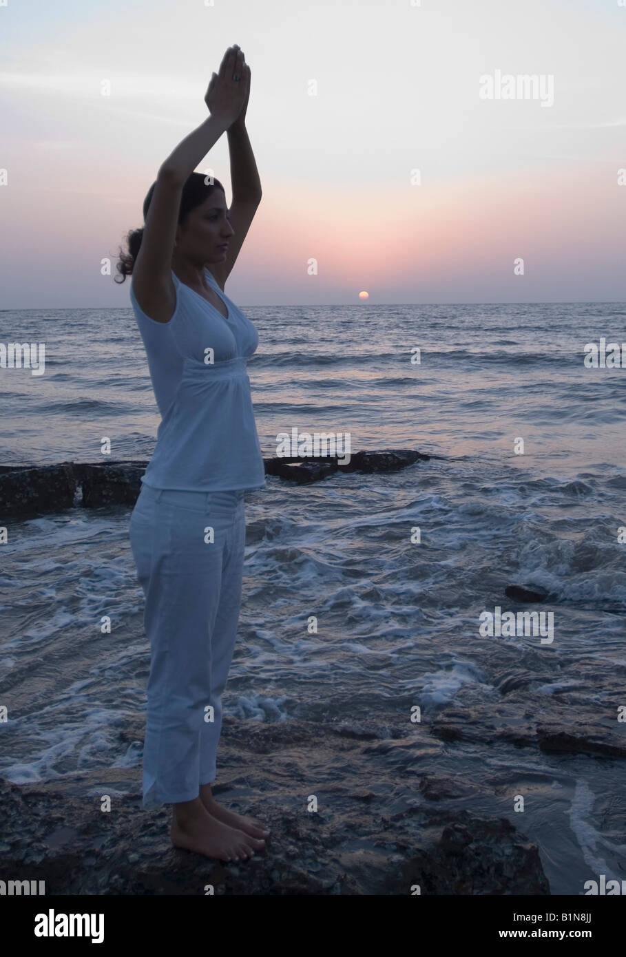 Side profile of a young woman meditating in a prayer position on the ...
