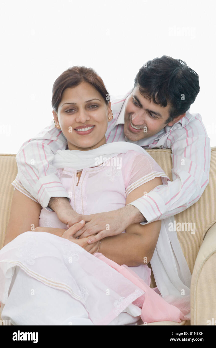 Mid adult man arm around a mid adult woman from behind and smiling ...