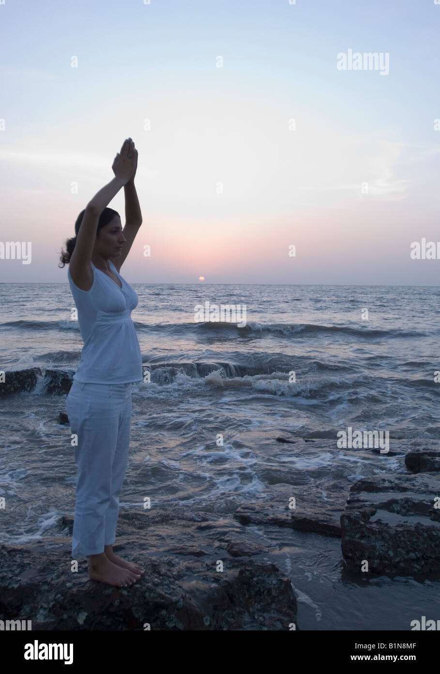 Side profile of a young woman meditating in a prayer position on the ...