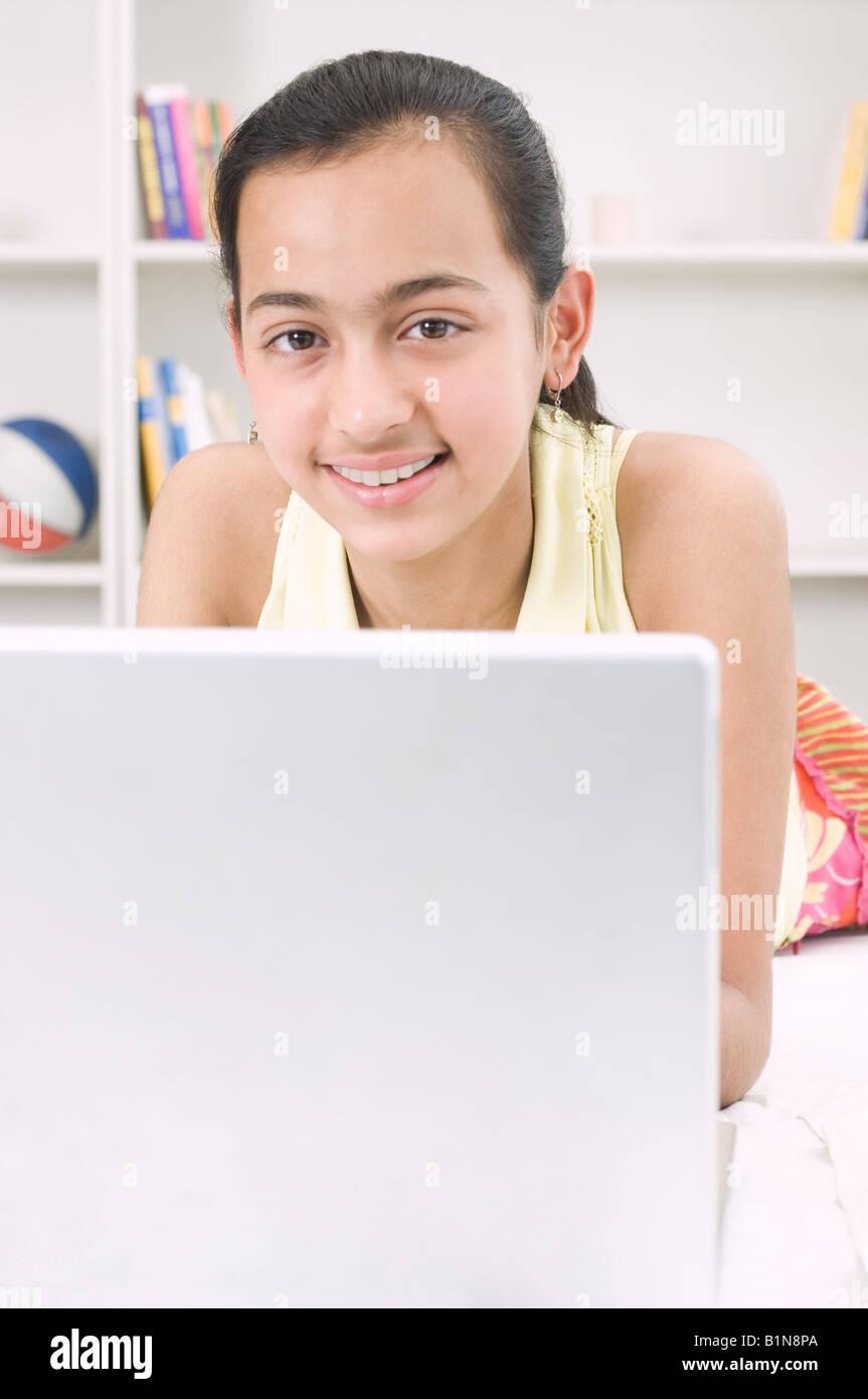 Portrait of a girl lying in front of a laptop Stock Photo - Alamy