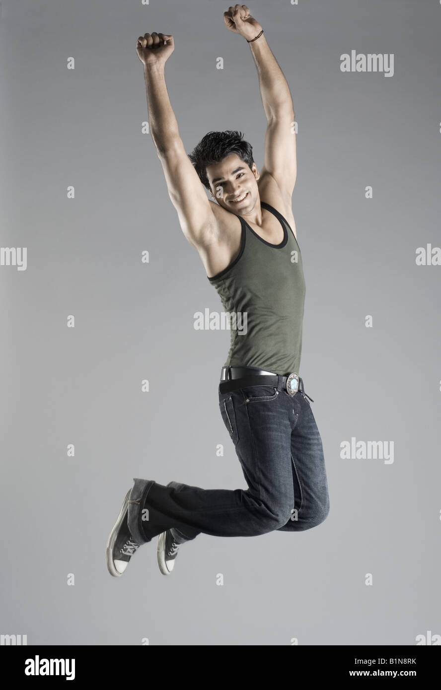 Portrait of a young man jumping with his arms raised and smiling Stock ...