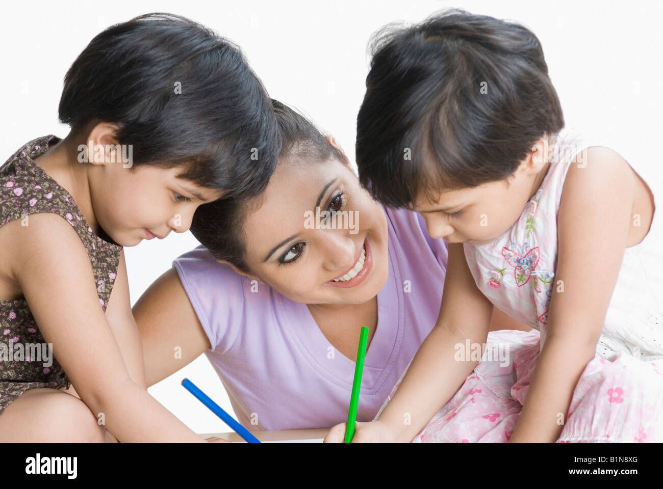 Two girls drawing in sketch pads and their mother looking at them Stock ...