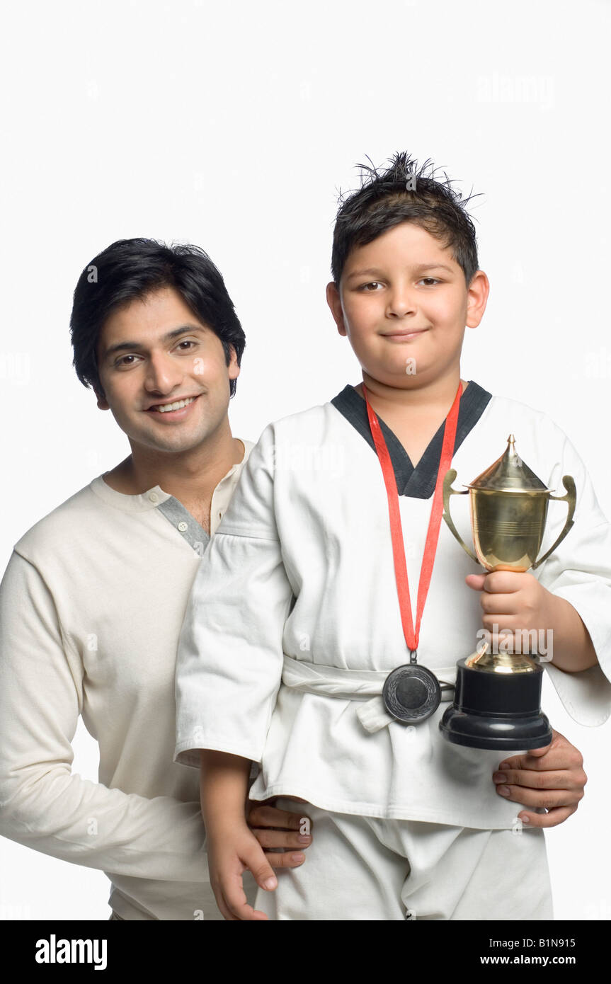 Portrait of a young man with his son holding a trophy Stock Photo - Alamy