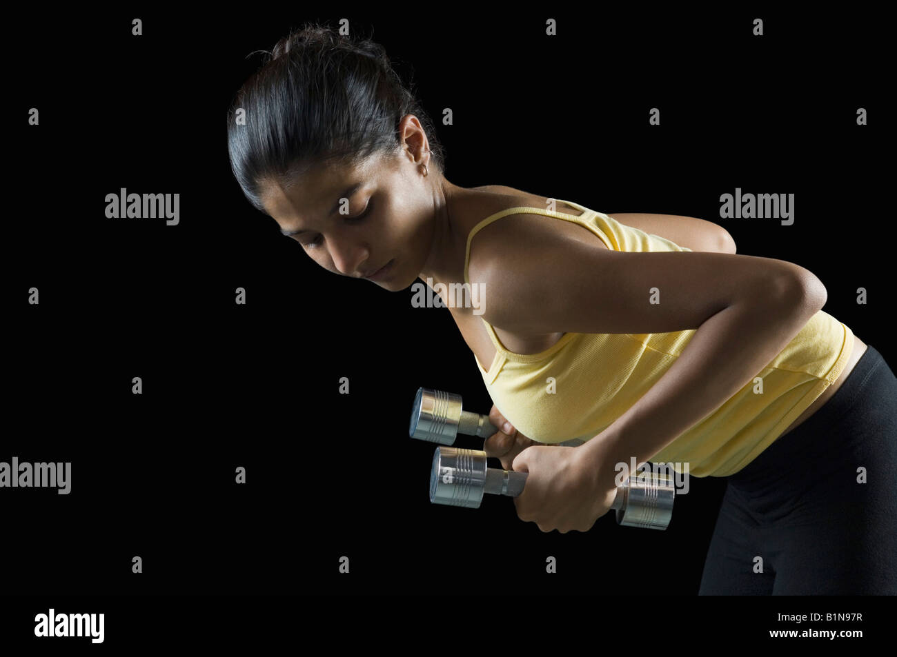 Side profile of a young woman exercising with dumbbells Stock Photo - Alamy