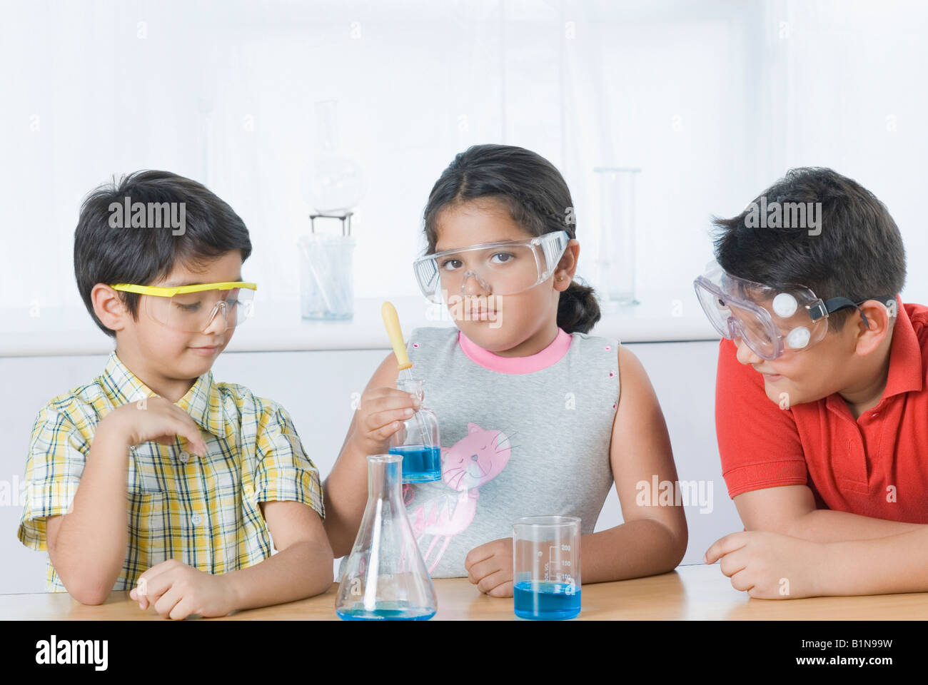 Portrait of a girl with other students doing scientific experiment in a ...