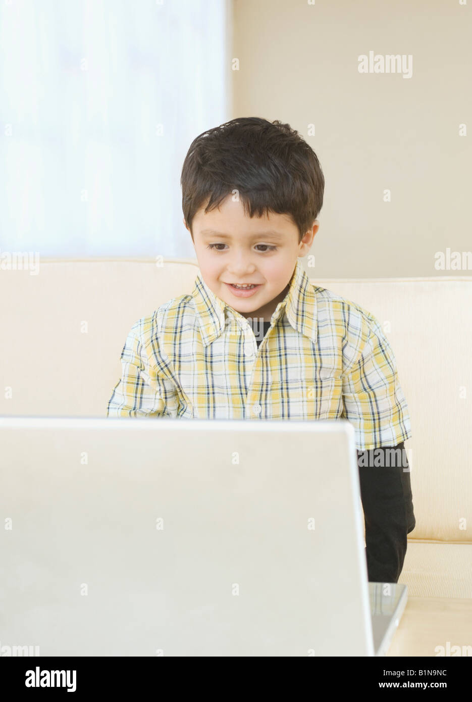 Boy standing at a table and using a laptop Stock Photo - Alamy