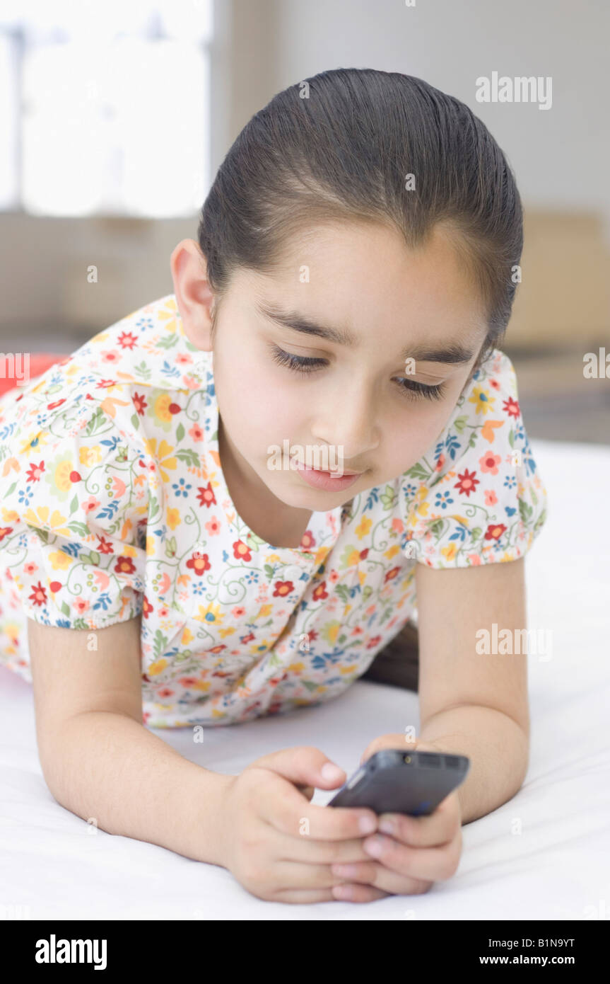 Girl lying on the bed and holding a mobile phone Stock Photo - Alamy