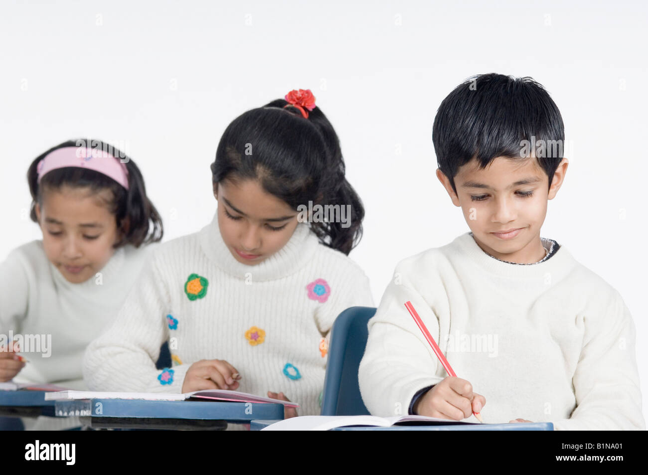 Three students sitting in a classroom and studying Stock Photo - Alamy