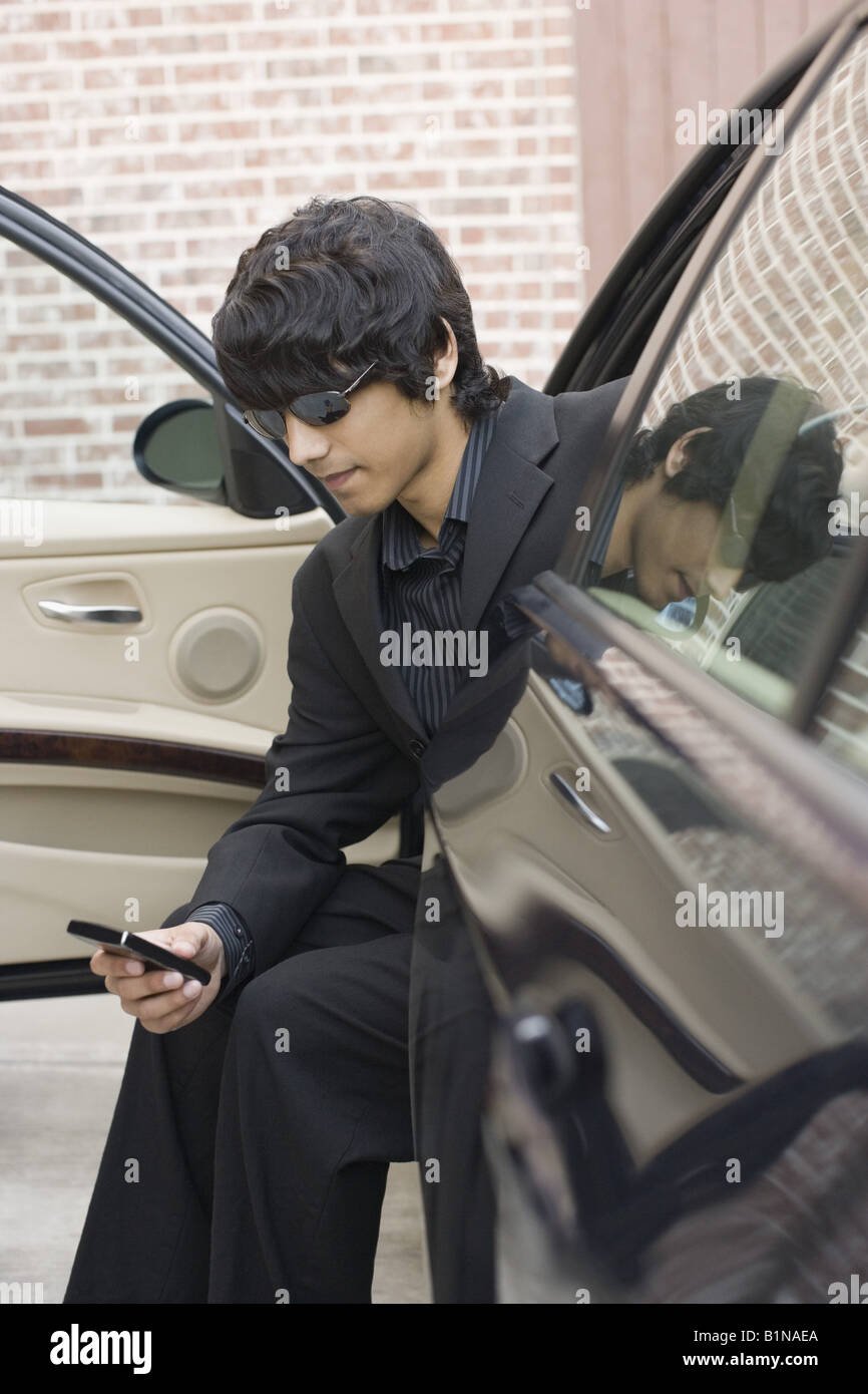 Side profile of a teenage boy sitting in a car and using a flip phone ...