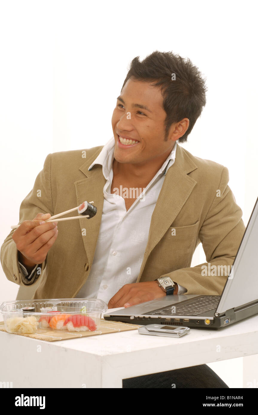 Asian man is eating sushi on his desk Stock Photo - Alamy