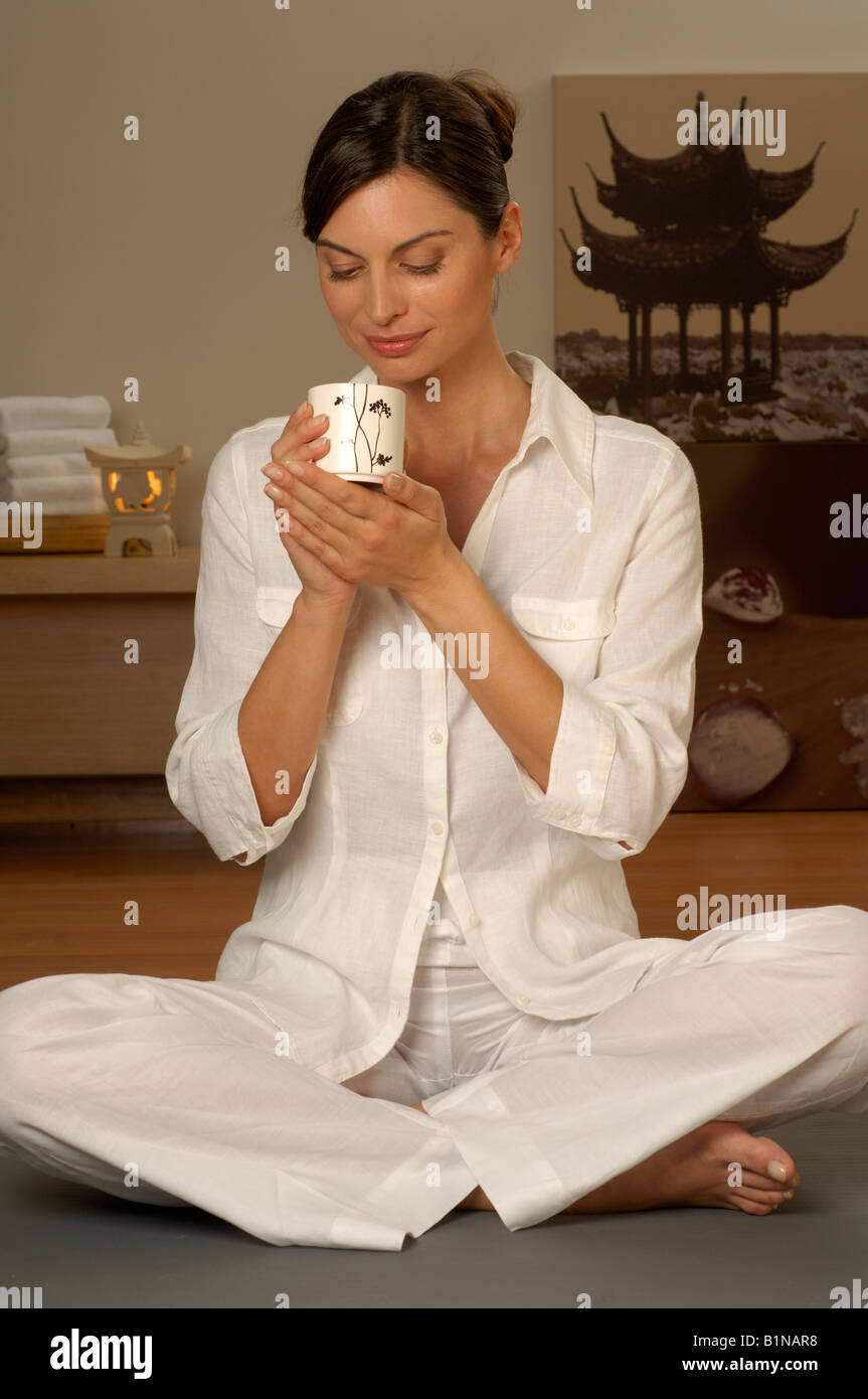 Woman sitting cross-legged with a cup of tea Stock Photo - Alamy