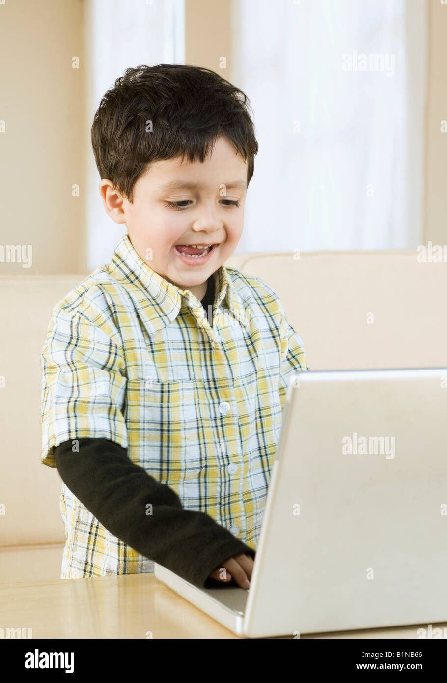Boy standing at a table and using a laptop Stock Photo - Alamy