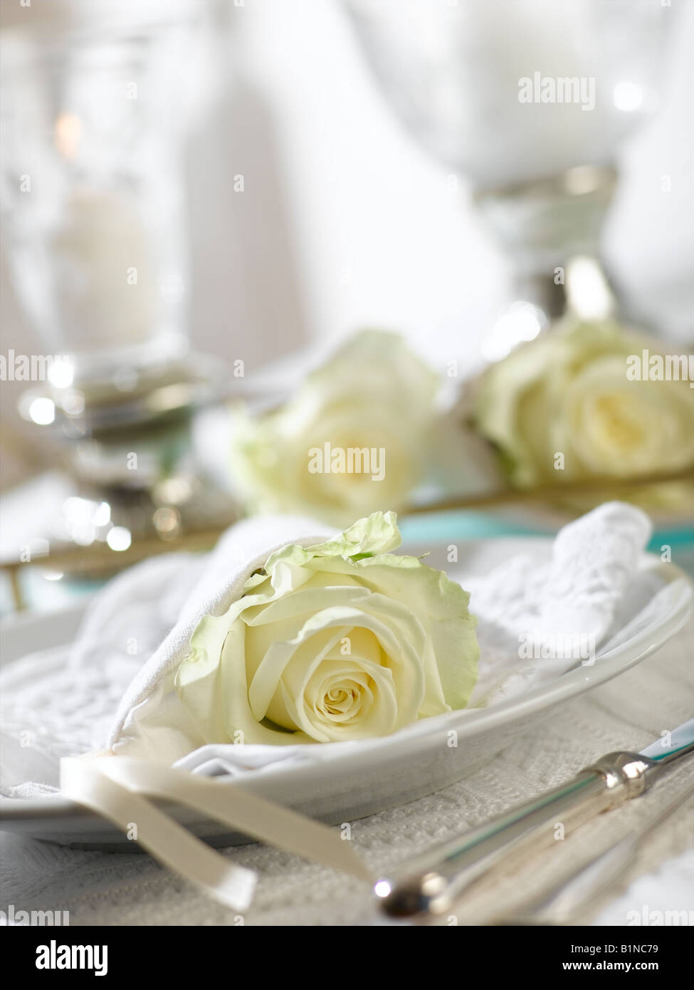 Place setting with a white rose wrapped in a napkin Stock Photo - Alamy