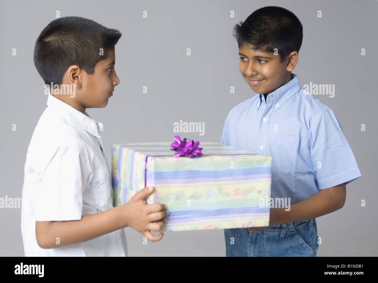 Side profile of a boy giving a gift to another boy and smiling Stock ...
