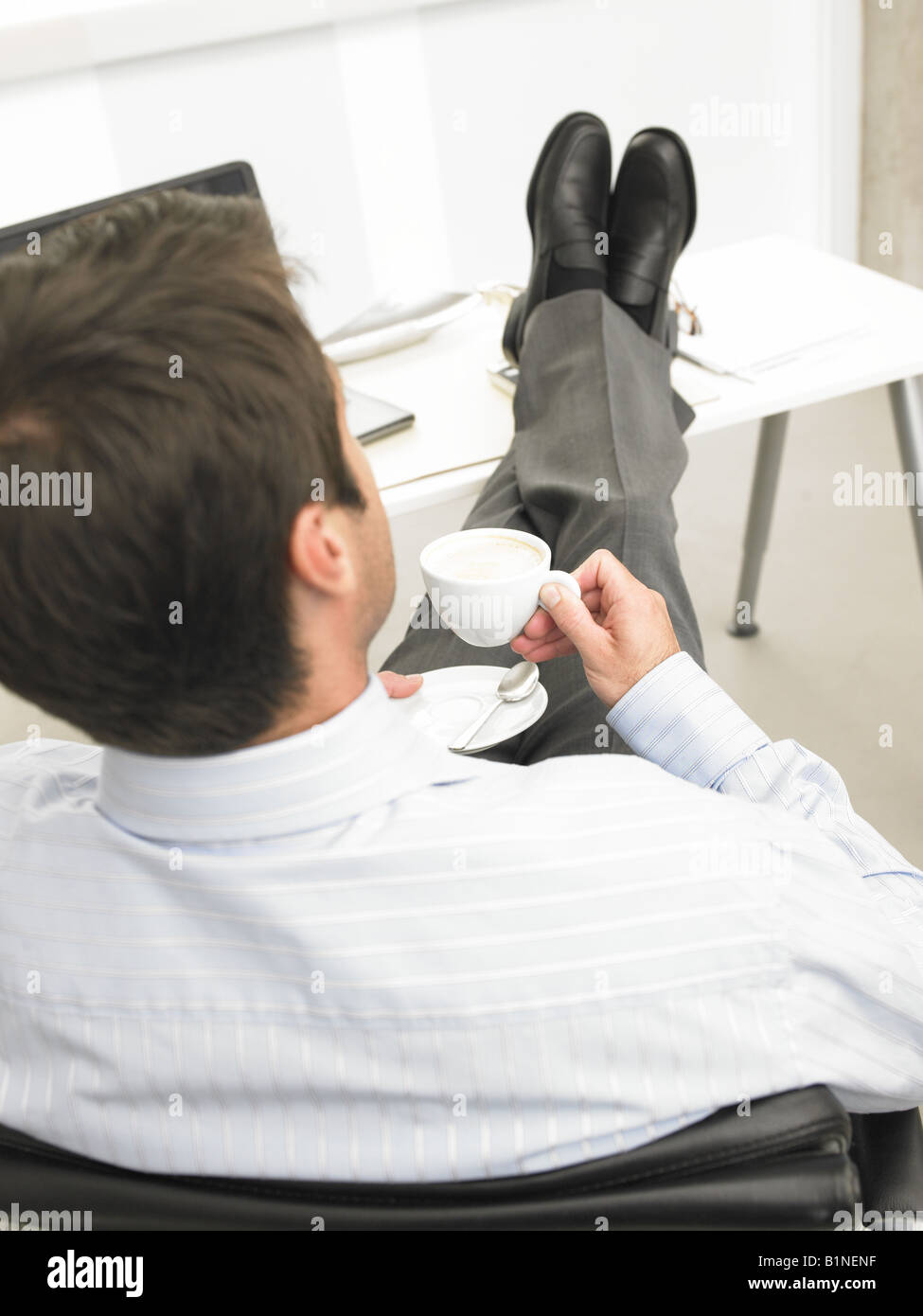 Business man with feet on desk is drinking coffee Stock Photo - Alamy
