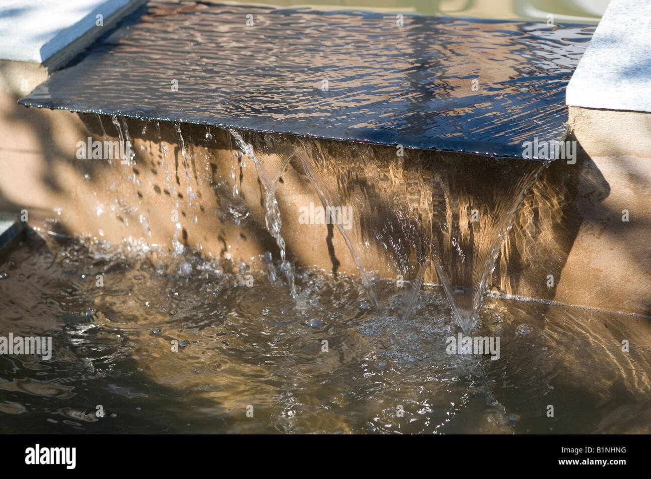 a waterfall pouring over a slate garden wall Stock Photo - Alamy