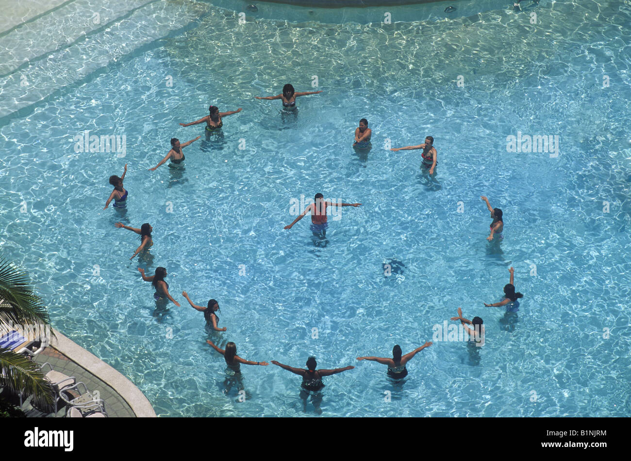 Group of people doing a group aerobic exercise in hotel swimming pool ...