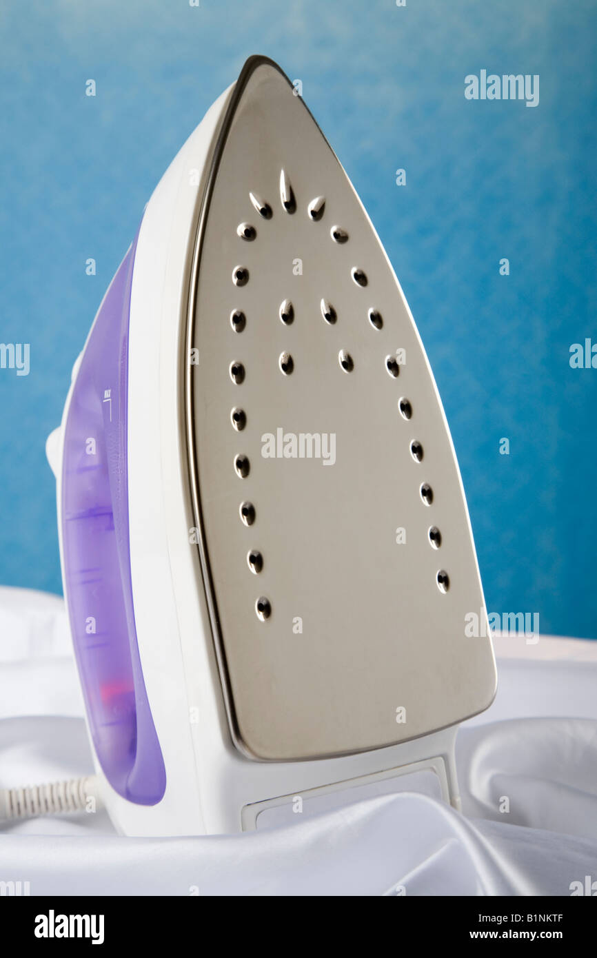An iron standing on a white cloth Stock Photo - Alamy