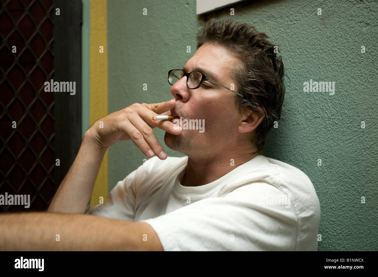Man leaning against wall smoking cigarette hi-res stock photography and ...
