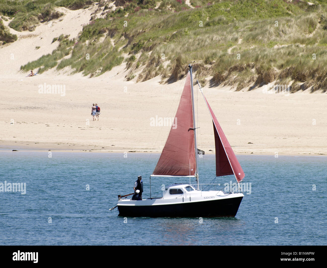 Small yacht sailing past a sandy beach in Cornwall Stock Photo - Alamy