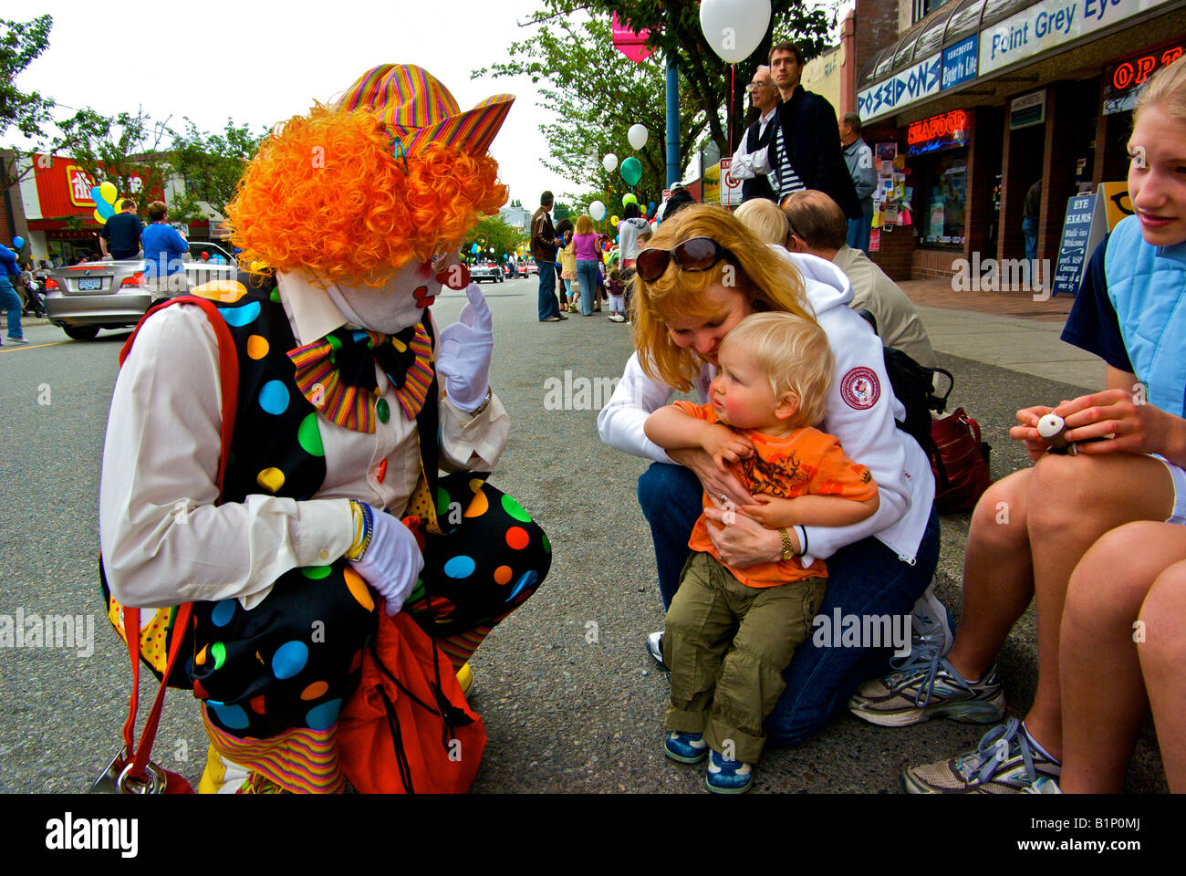 Mother holding her unsure baby first encounter with an orange wigged ...