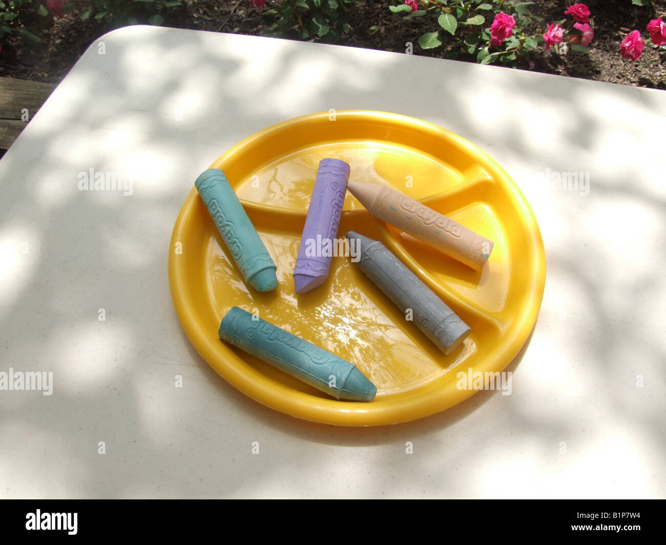 Large chalk of various colors on yellow plastic plate on white table ...
