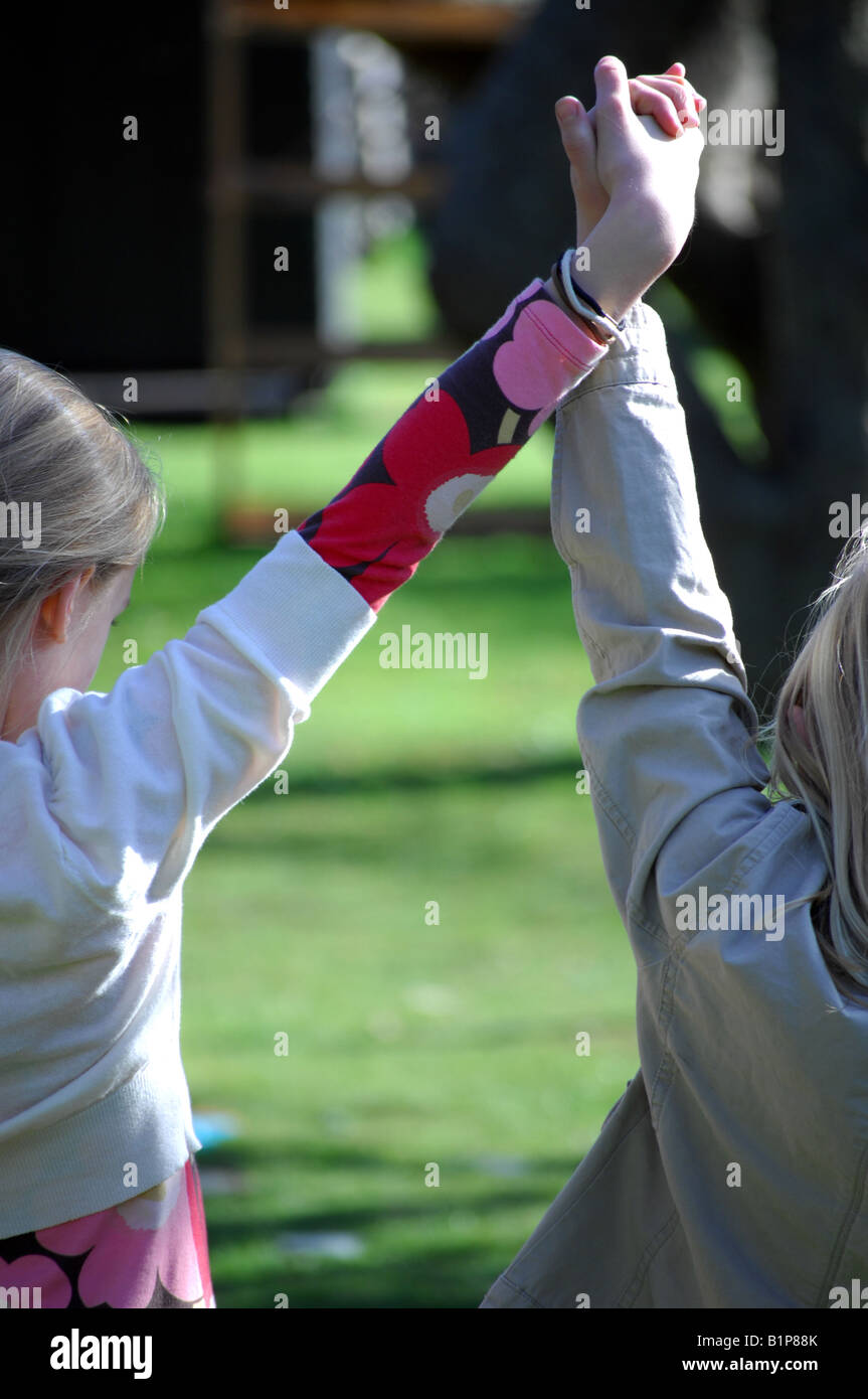 Photograph of two friends holding hands whilst playing games outside ...