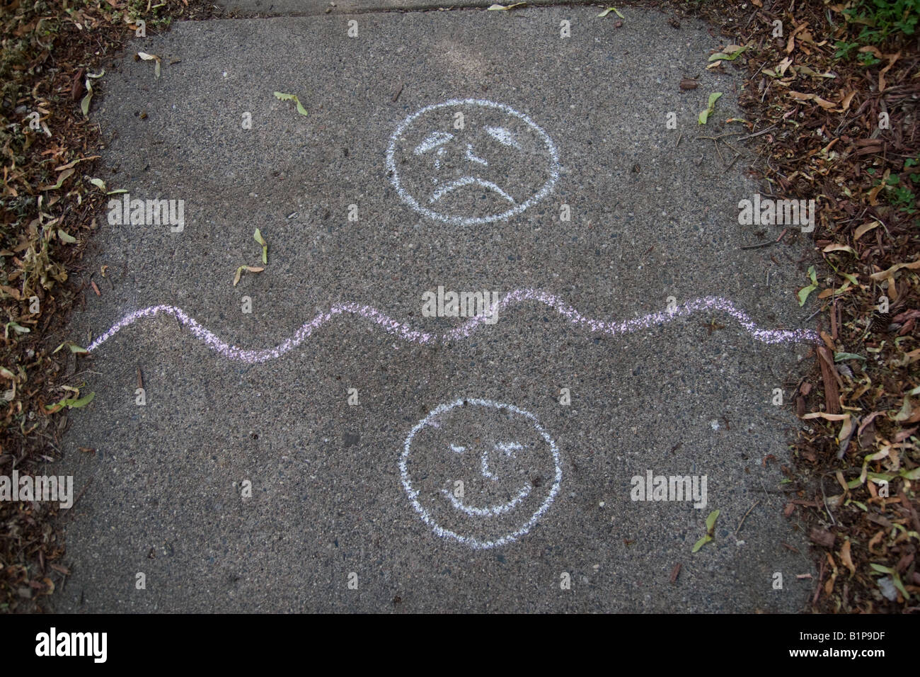 A sidewalk chalk drawing of a happy face and a sad face Stock Photo - Alamy