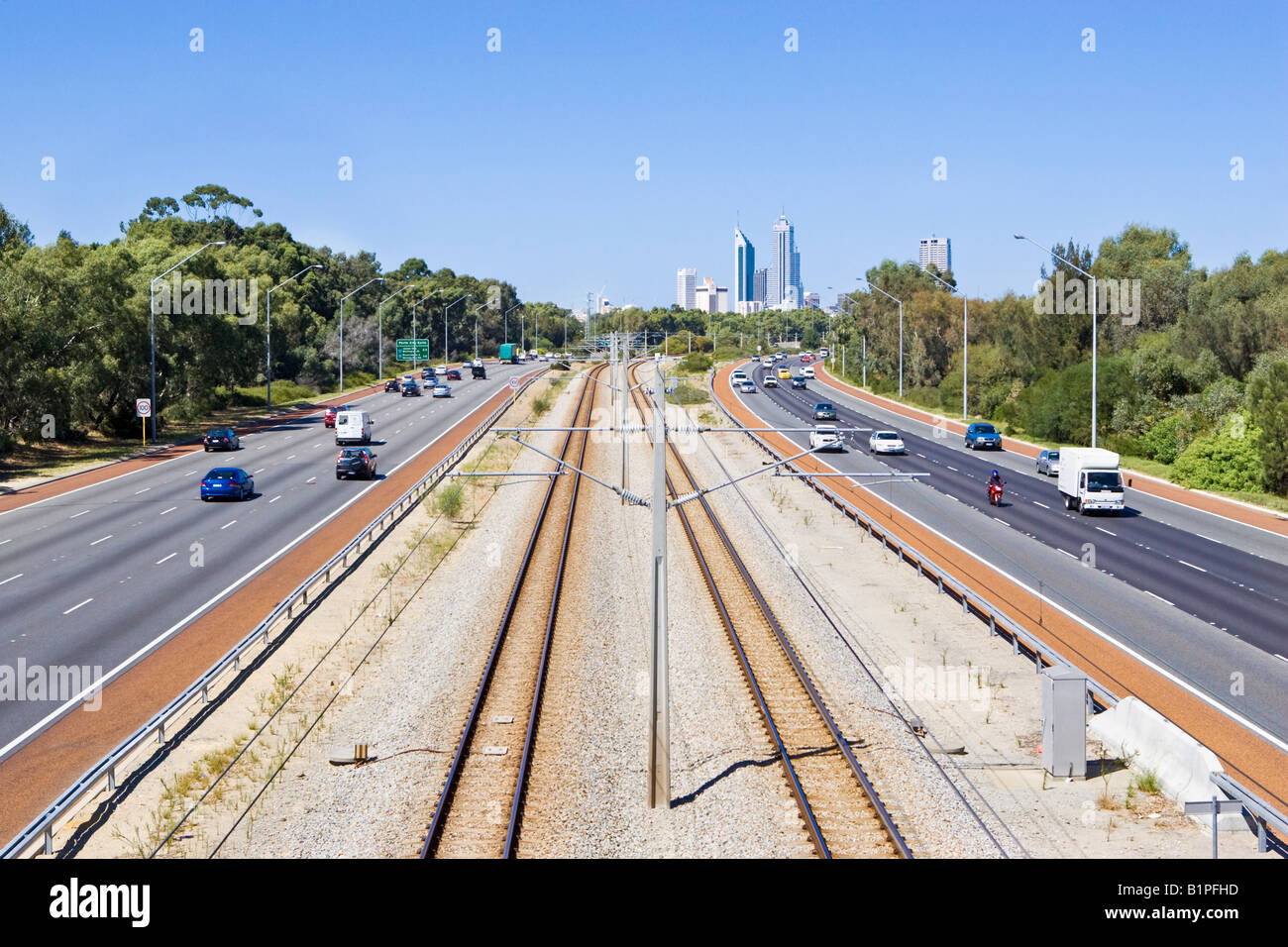 Commuter train tracks between a major road. Mitchell Freeway, Perth ...