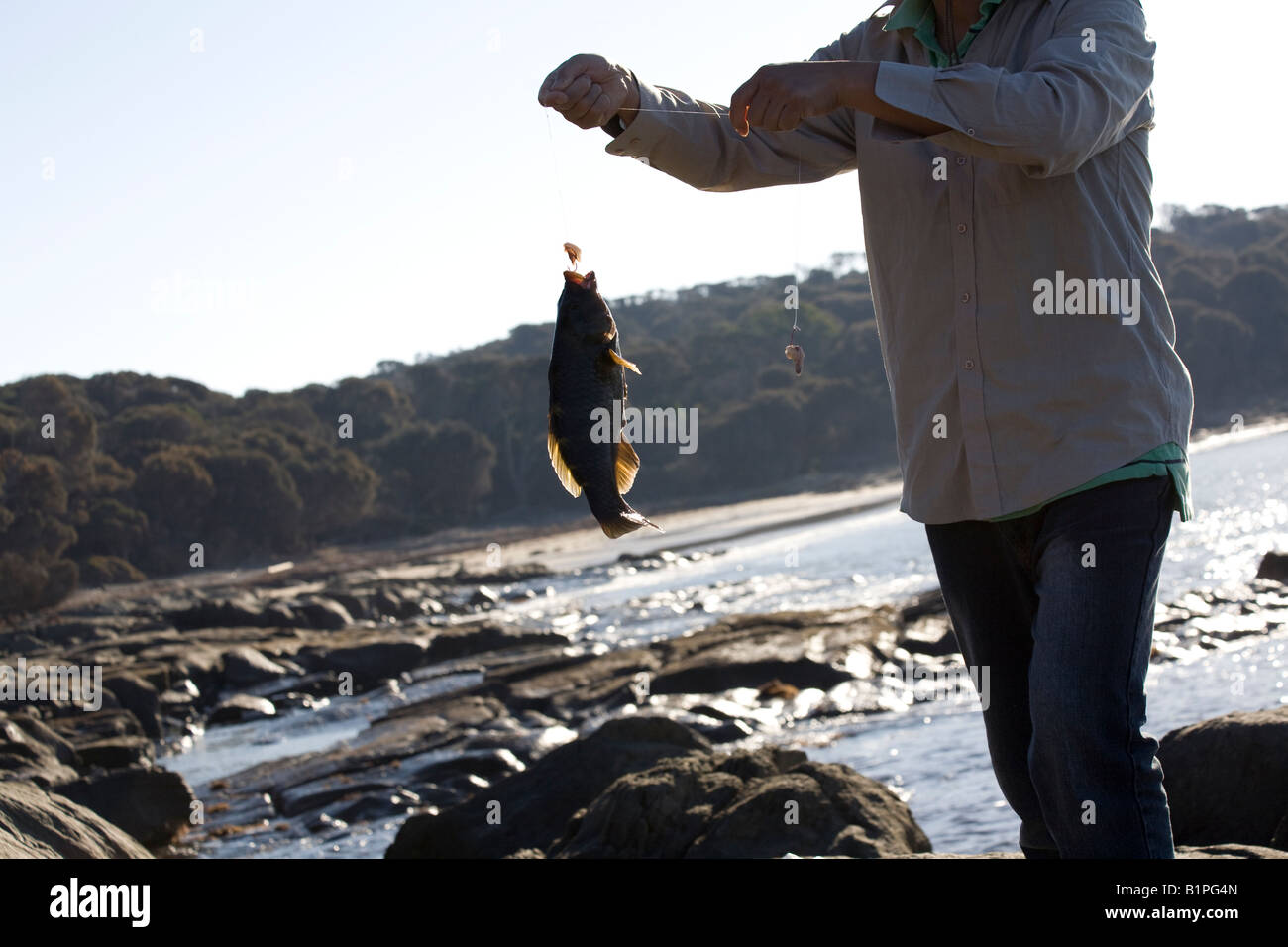 A man carries a fish he has just caught Stock Photo - Alamy