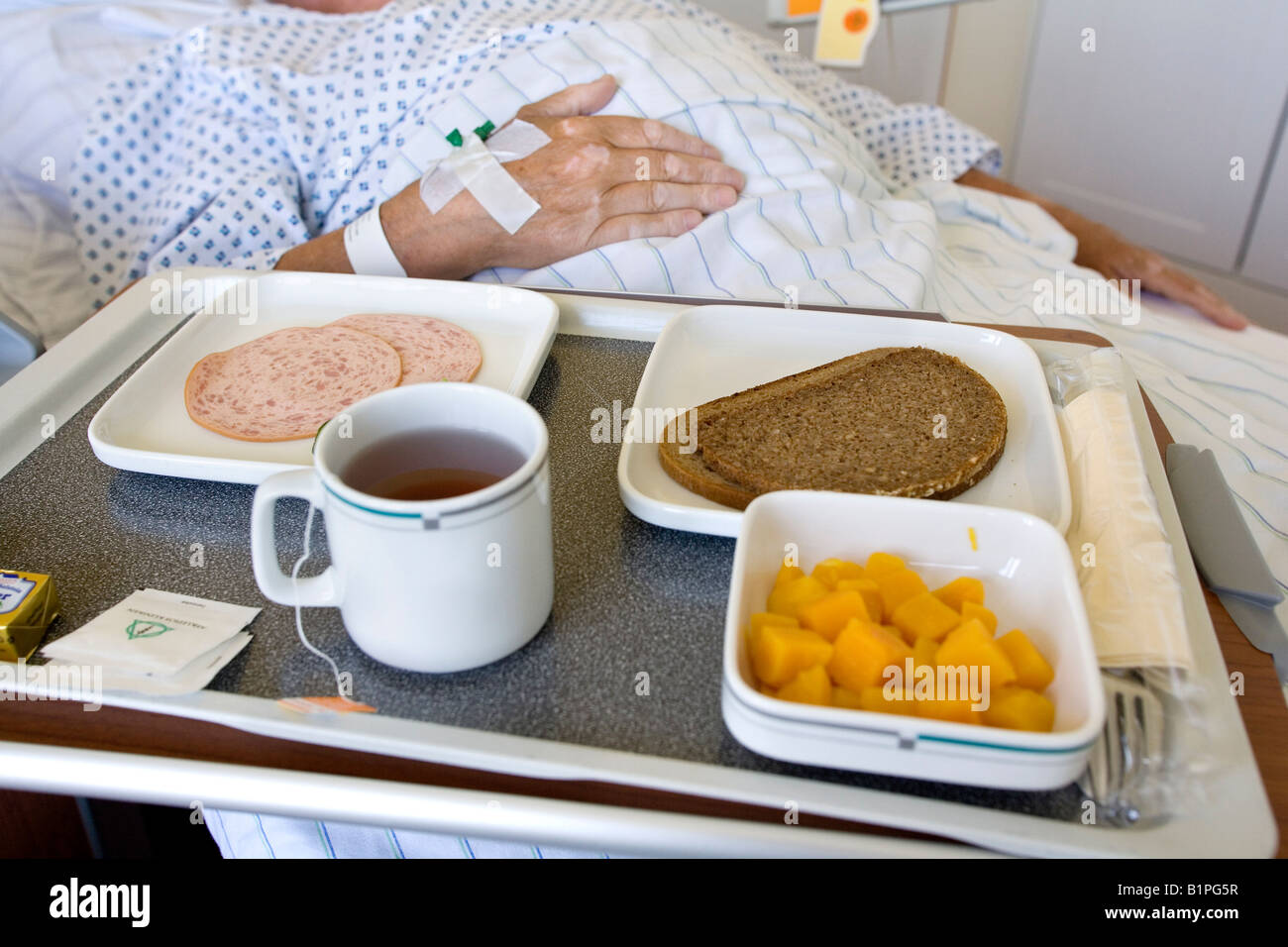 Sick senior with his supper in the hospital bed of a hospital ward for ...