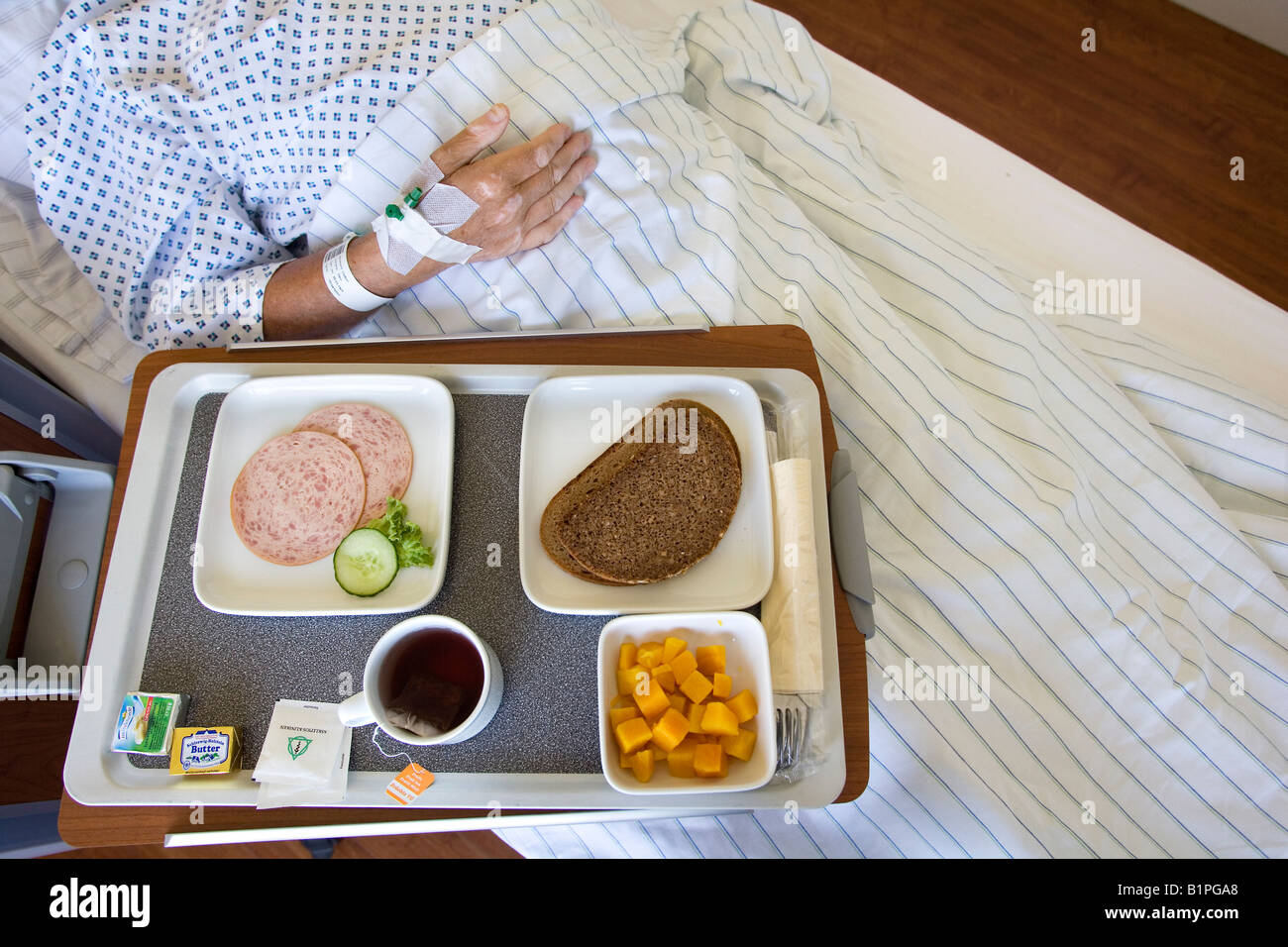 Sick senior with his supper in the hospital bed of a hospital ward for ...
