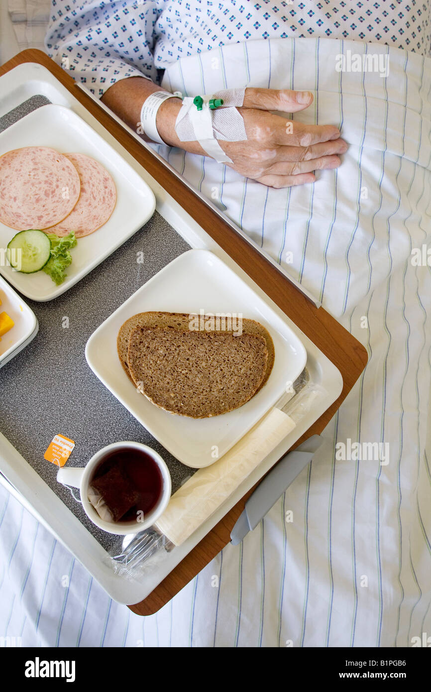 Sick senior with his supper in the hospital bed of a hospital ward for ...