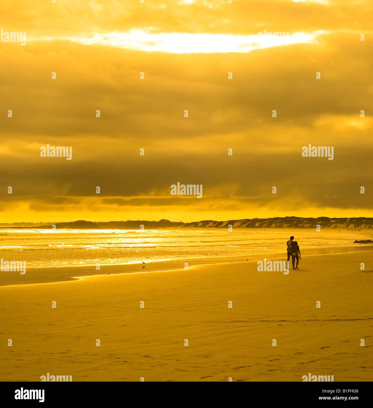 young couple walking in sunset beach Stock Photo - Alamy