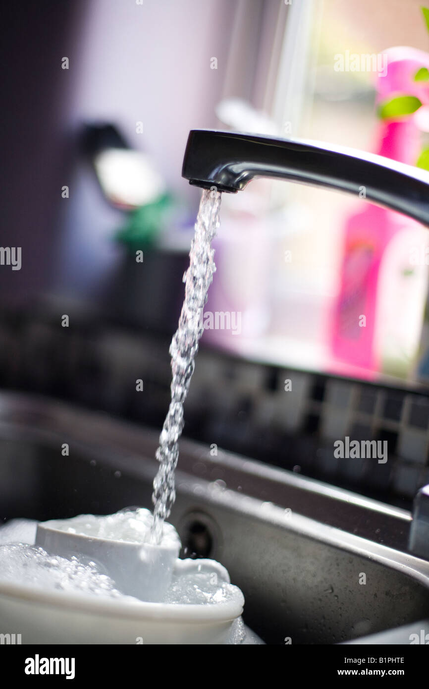 a tap running water washing the dishes Stock Photo - Alamy