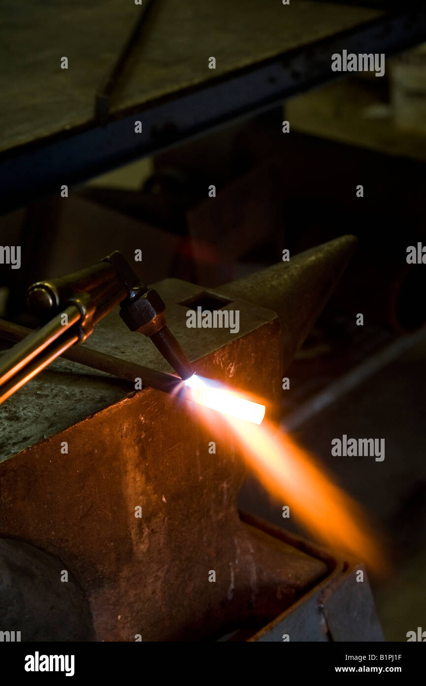 Old style hand made iron workers in a small work shop force shaping a ...