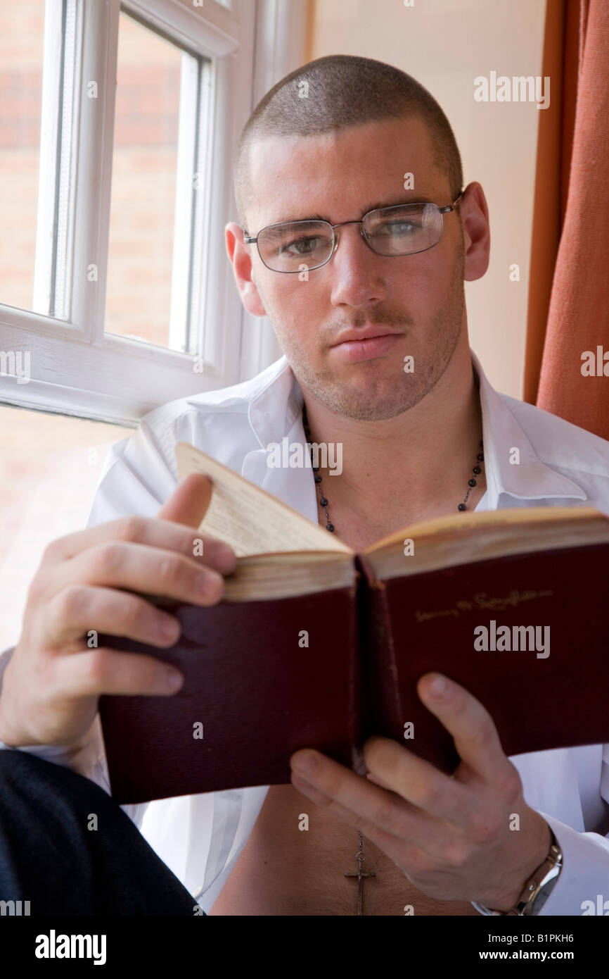 Good looking young man sitting in window reading a book Stock Photo - Alamy