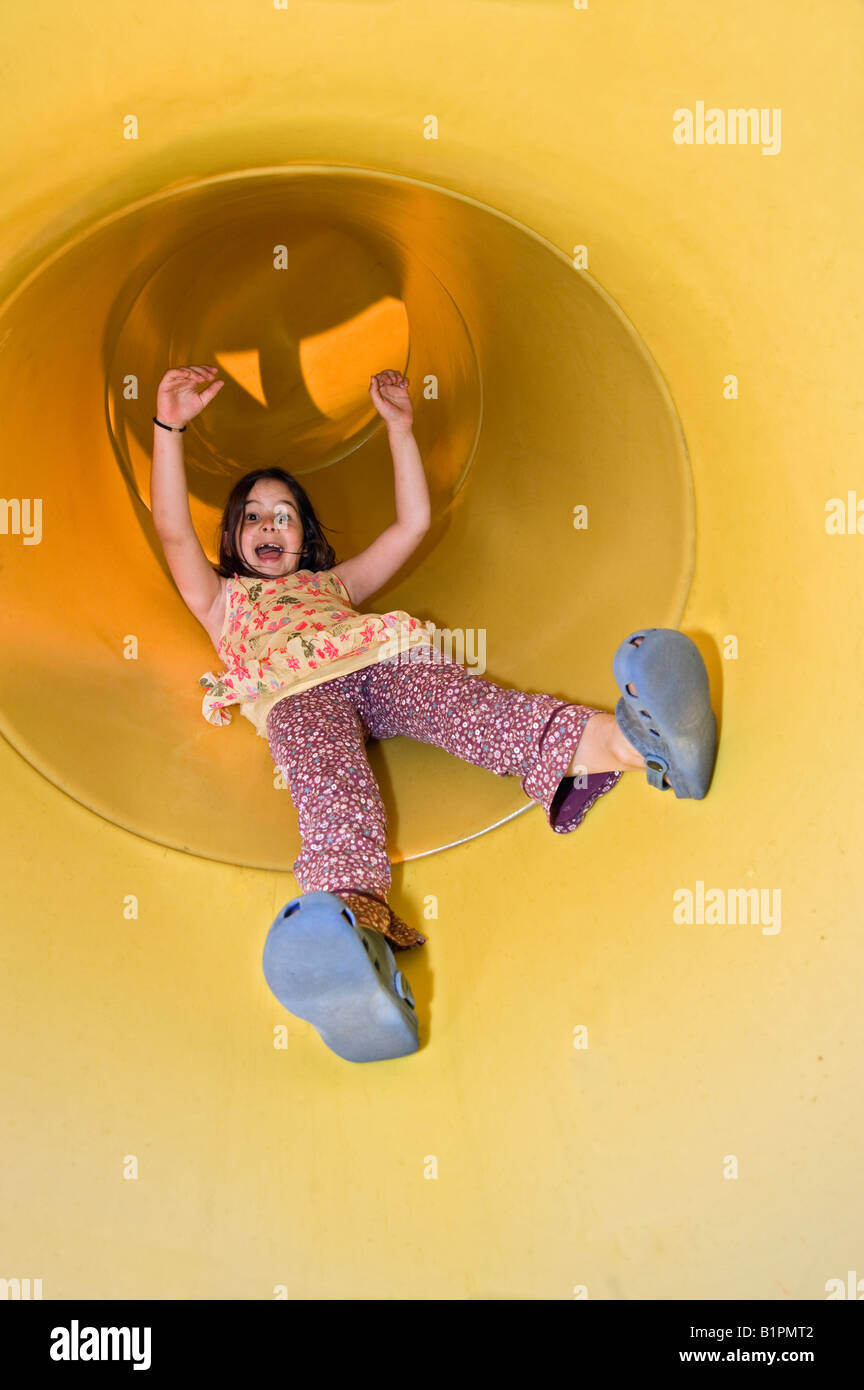 girl sliding in a yellow tube slide in a playground Stock Photo - Alamy