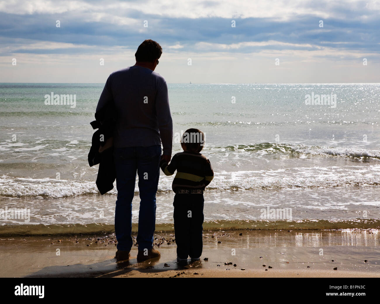 A Man And Three Year Old Boy Look At Small Waves On Bournemouth Beach a-man-and-three-year-old-boy-look-at-small-waves-on-bournemouth-beach