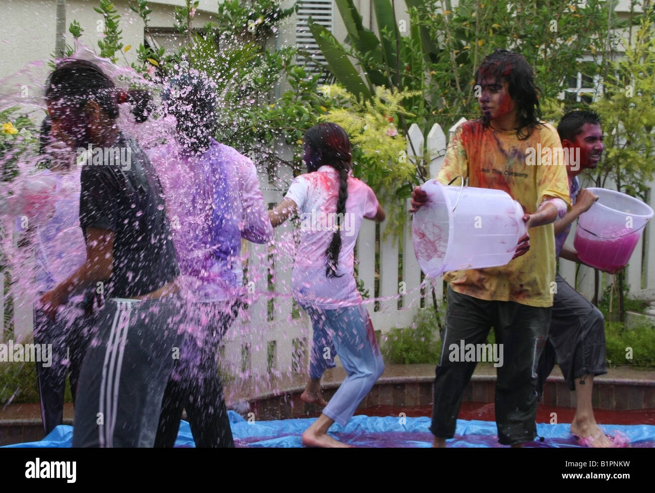 Teenagers and children having fun with coloured water and holi powder ...