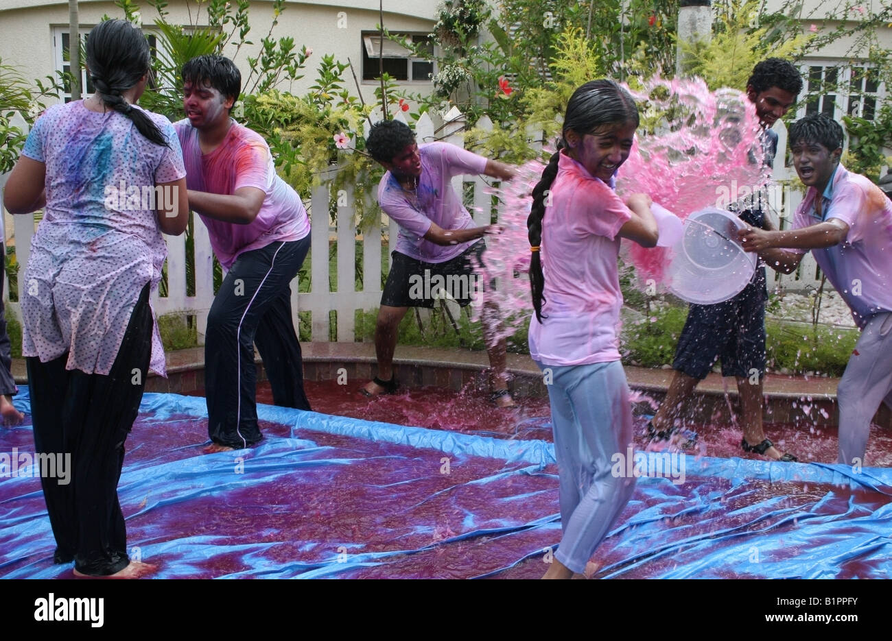Teenagers and children having fun with coloured water and holi powder ...