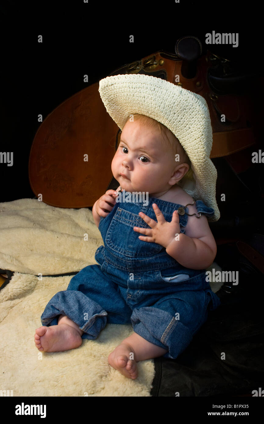 Little baby boy dressed like a cowboy sitting in front of saddle Stock ...